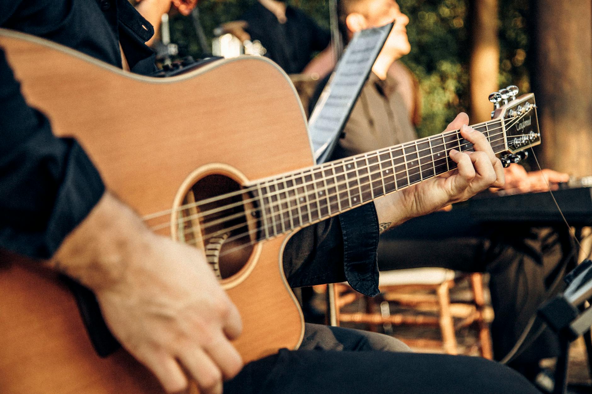 Live musician performing guitar at an outdoor evening event