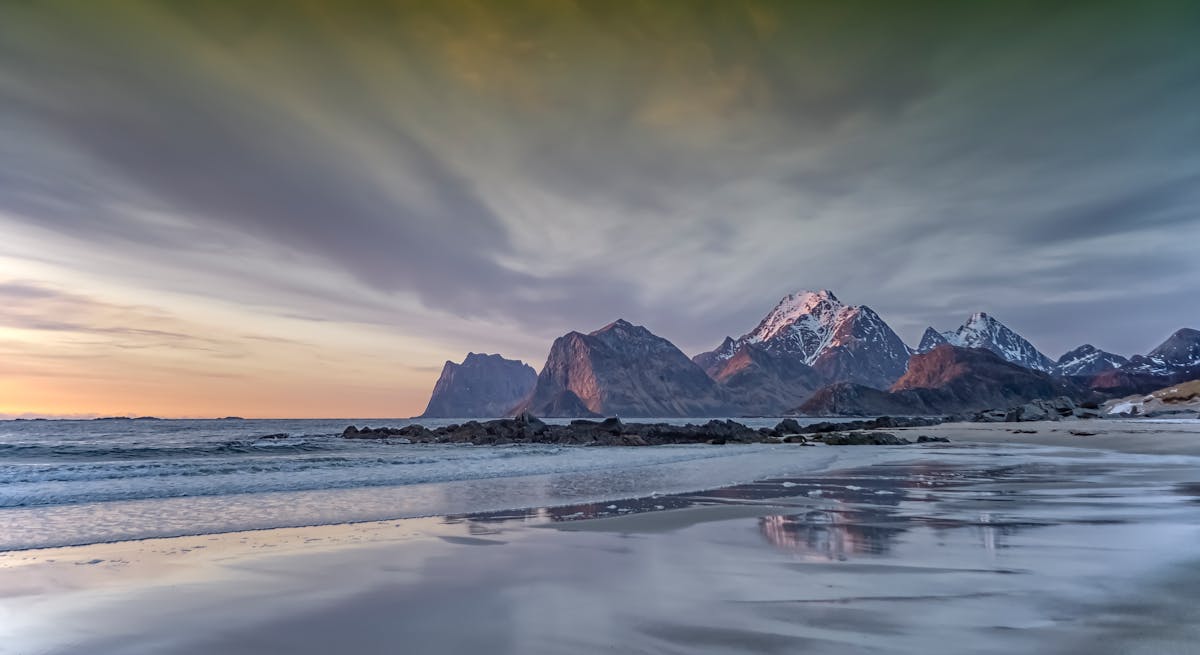 Ethereal view of Lofoten Islands coastline at sunset with snow-capped mountains
