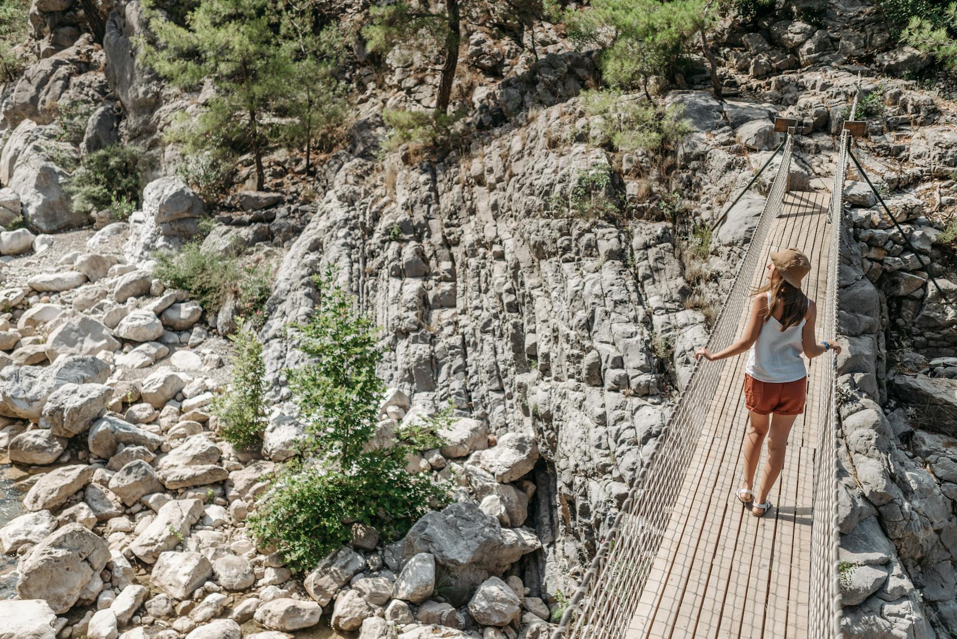 Woman crossing a suspension bridge over rocky canyon landscape