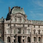 The Louvre Museum facade under a clear blue sky in Paris