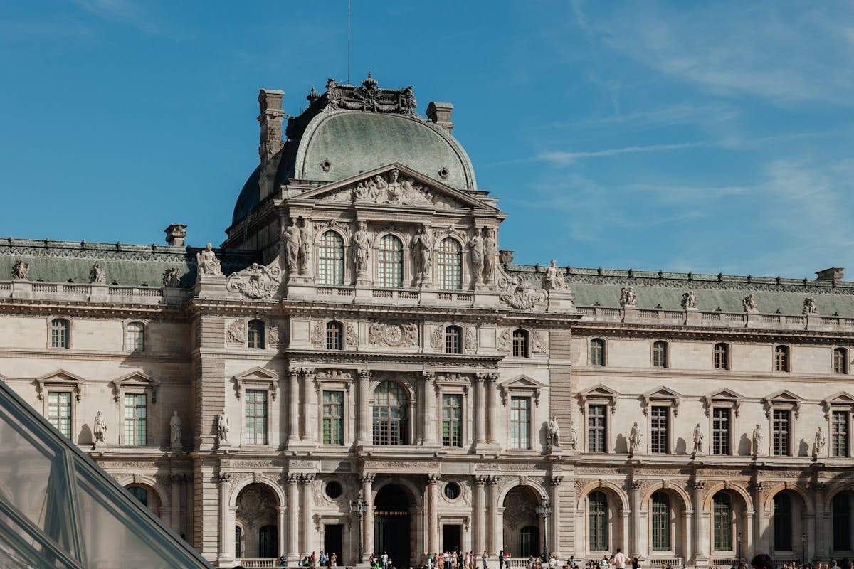 The Louvre Museum facade under a clear blue sky in Paris