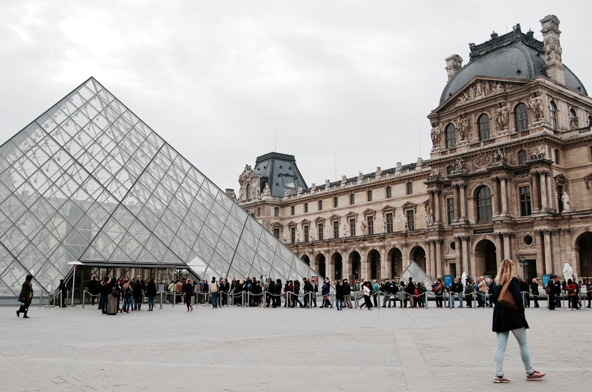 Visitors gathering at the glass pyramid entrance of the Louvre Museum in Paris