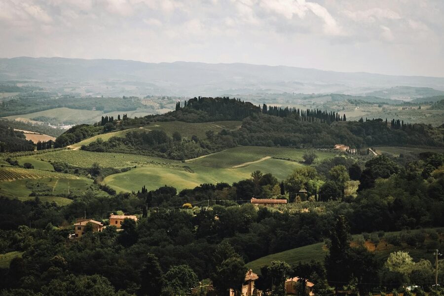 Idyllic Tuscany landscape with golden fields cypress trees and mountains under clear blue sky