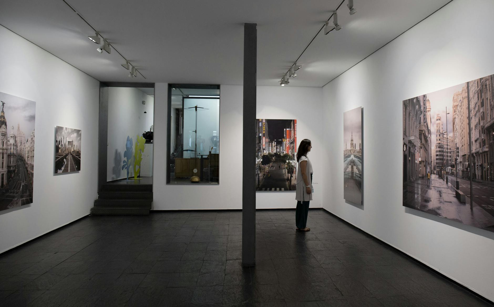 A woman observes landscape paintings displayed in a Madrid art gallery