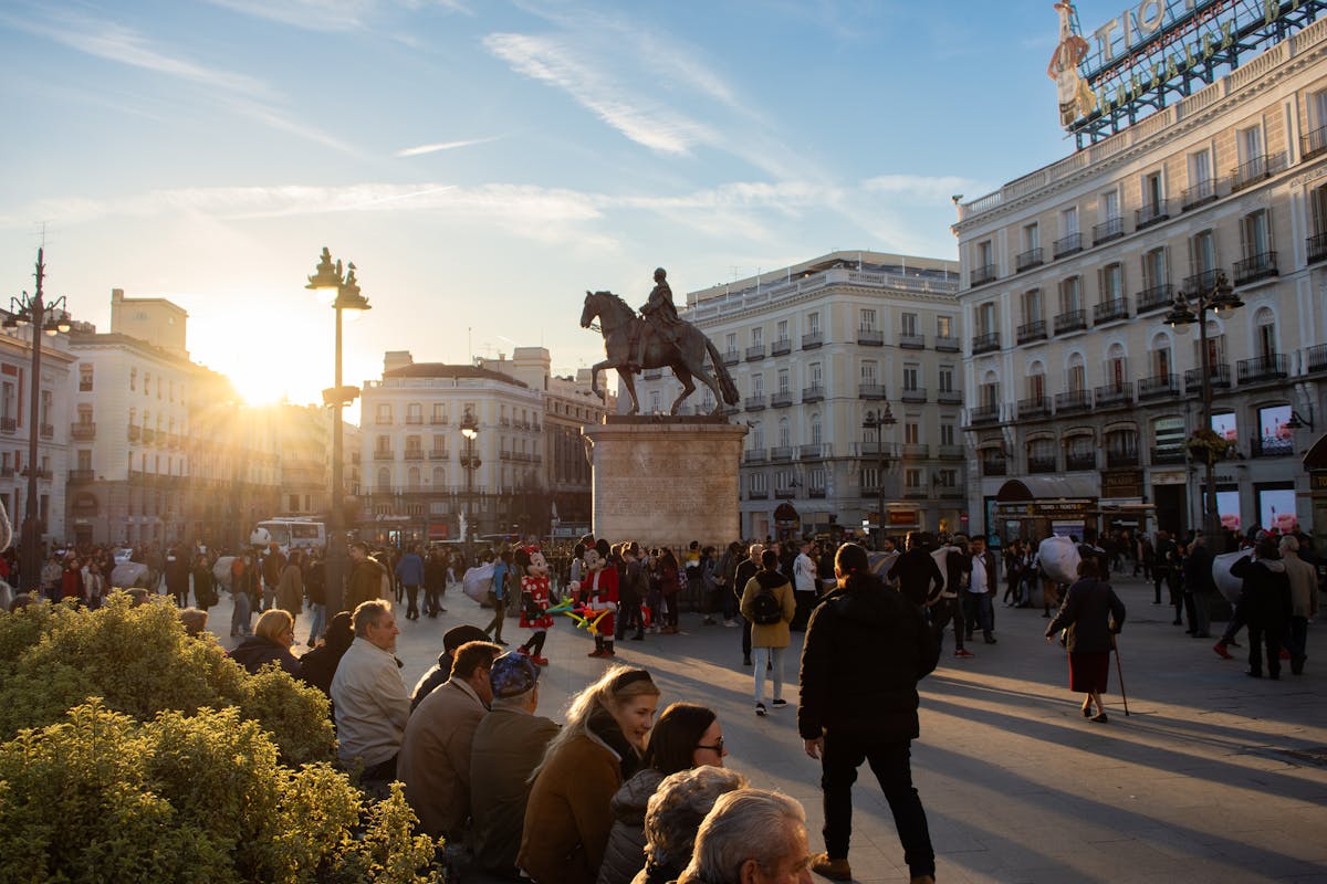 Puerta del Sol Madrid with travelers and statue at sunset