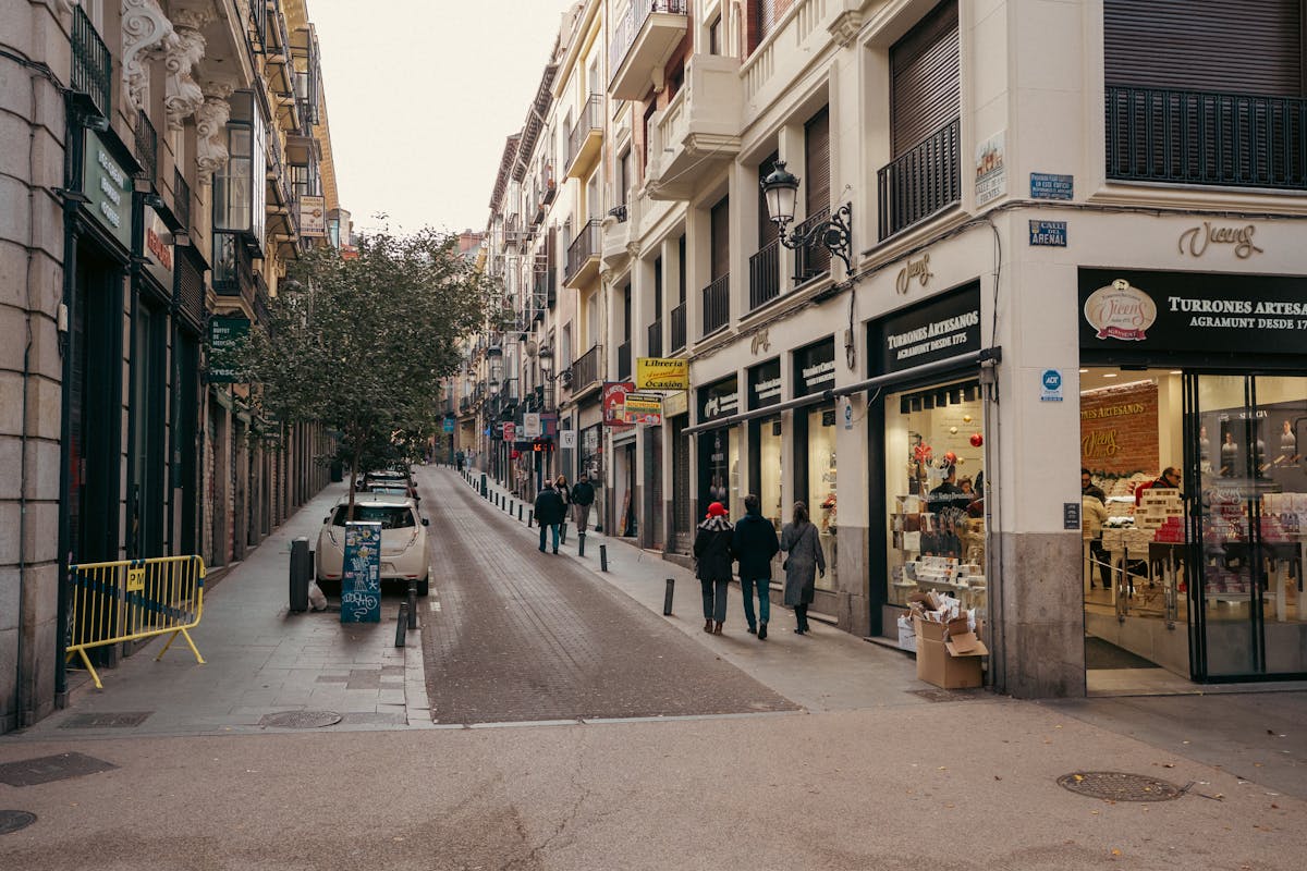 Narrow Calle de Arenal in Madrid with pedestrians and historic buildings on both sides