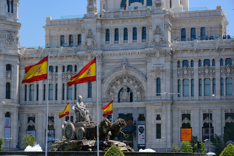 Cybele Palace in Madrid with flying Spanish flags and fountain