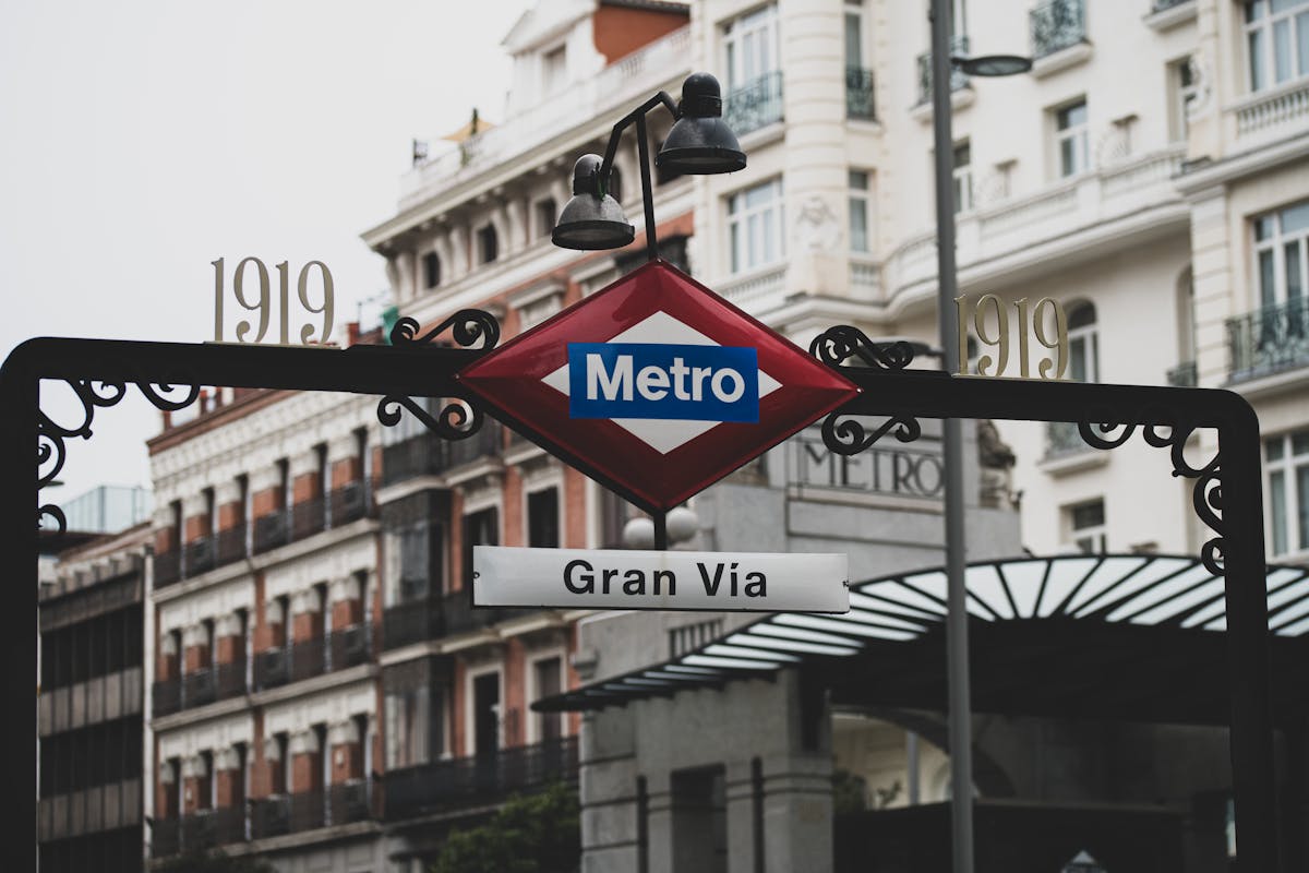 Entrance to Gran Via metro station in Madrid with historic buildings behind