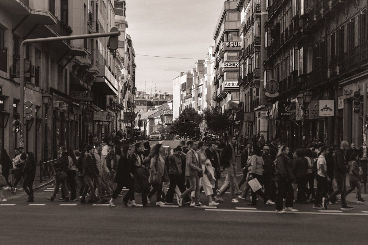 People crossing a busy Madrid street with historic buildings in the background