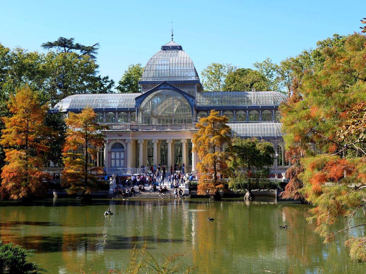 The Palacio de Cristal surrounded by autumn foliage at Retiro Park in Madrid