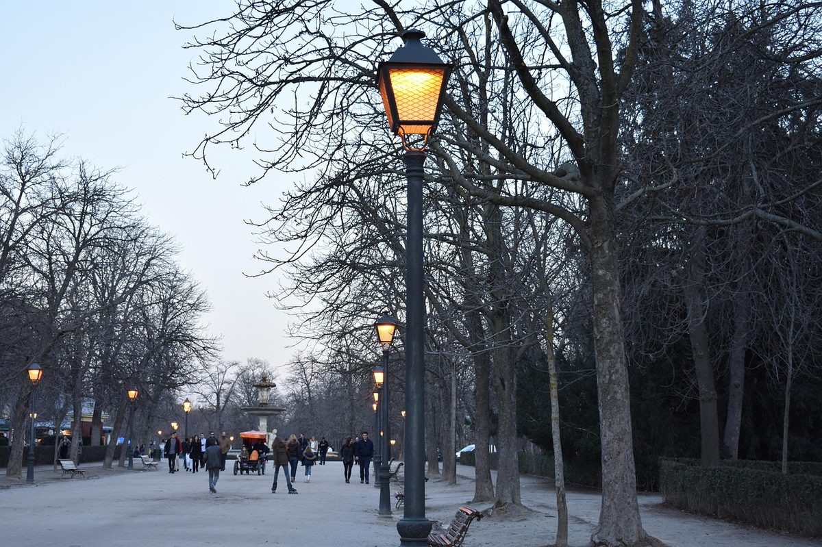 Lit pathway through Retiro Park Madrid at dusk
