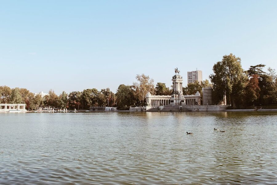 Monument and lake at El Retiro Park in Madrid under a clear sky