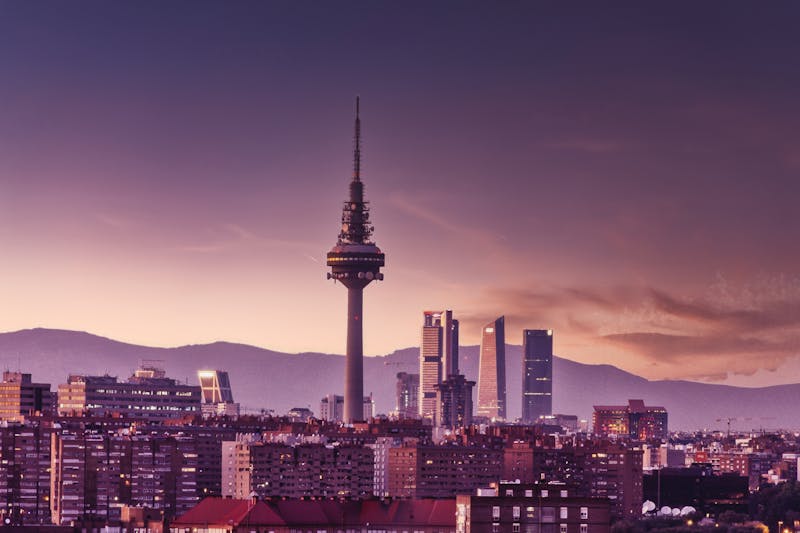 Madrid skyline at twilight featuring the Torrespana Tower and mountains in the background