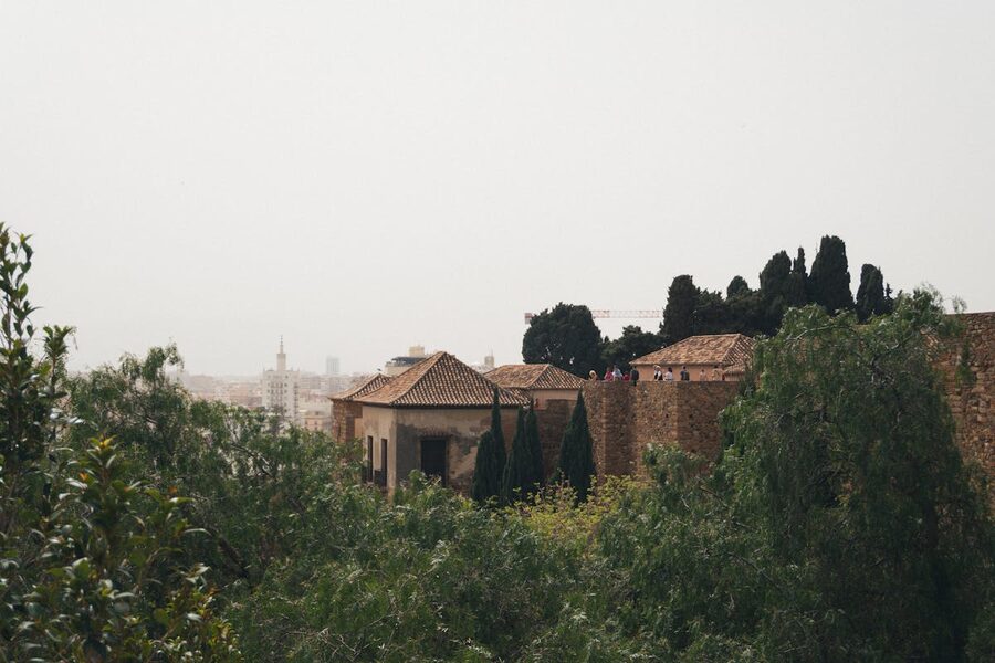 Historic stone walls and rooftops of the Alcazaba fortress surrounded by greenery in Malaga