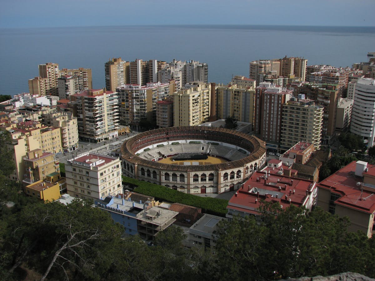 Aerial capture of Malaga bullring surrounded by modern buildings and Mediterranean sea