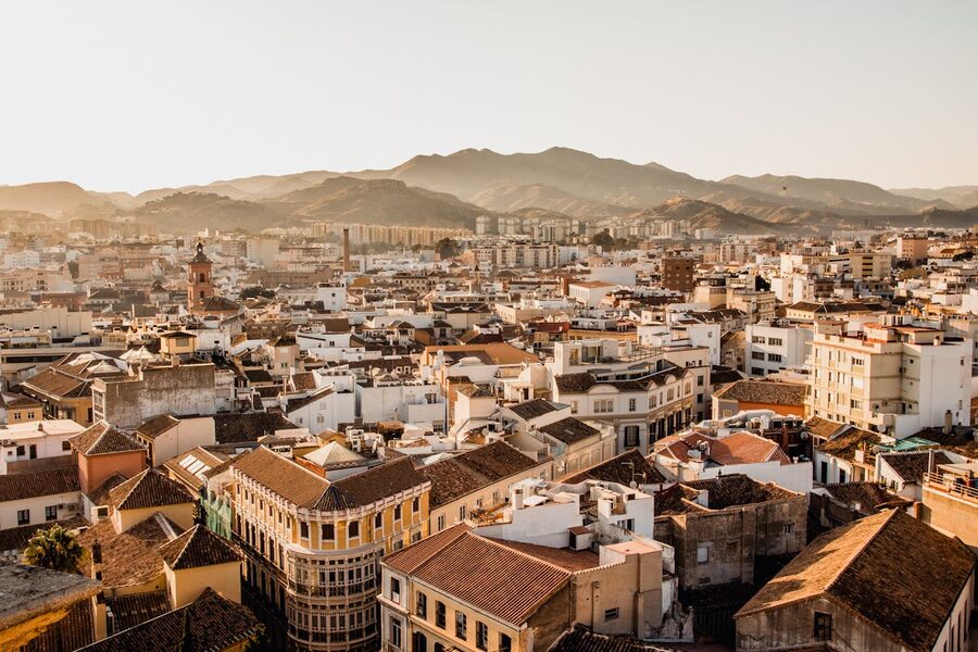 Aerial view of Malaga cityscape at sunset with mountains and Mediterranean Sea