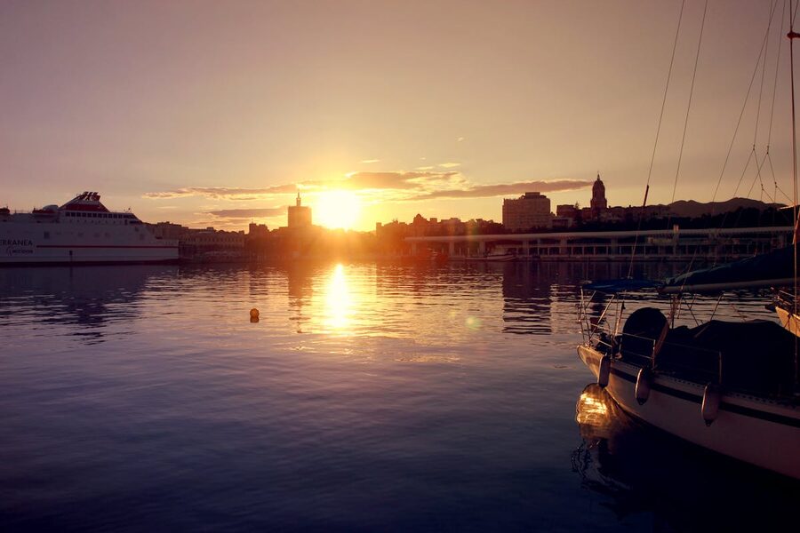 Beautiful sunset over Malaga harbour with boats reflecting on the water