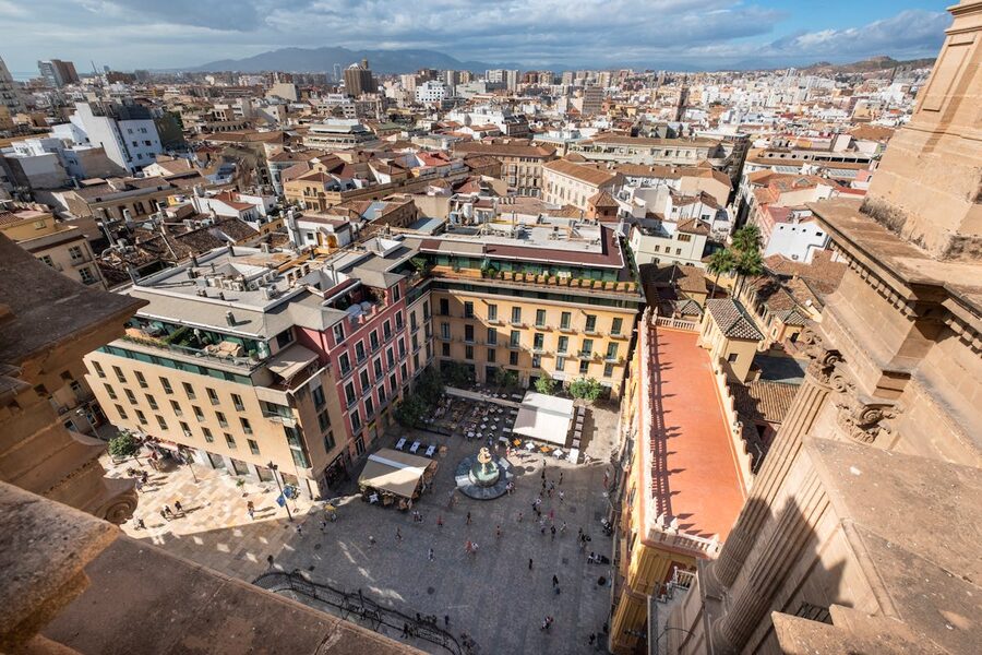 Aerial photograph of a large plaza in Malaga filled with people and surrounded by colourful buildings