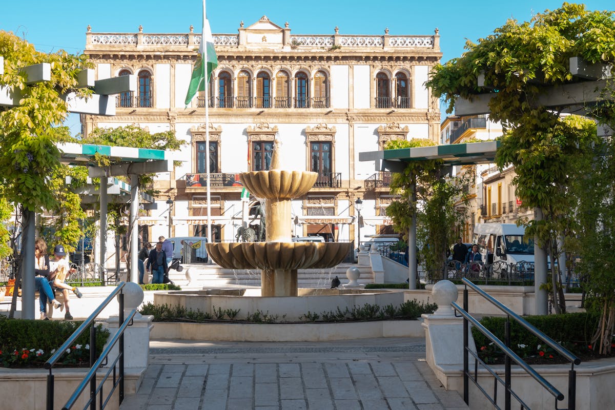 Charming fountain in a historic plaza with ornate building in Malaga Spain