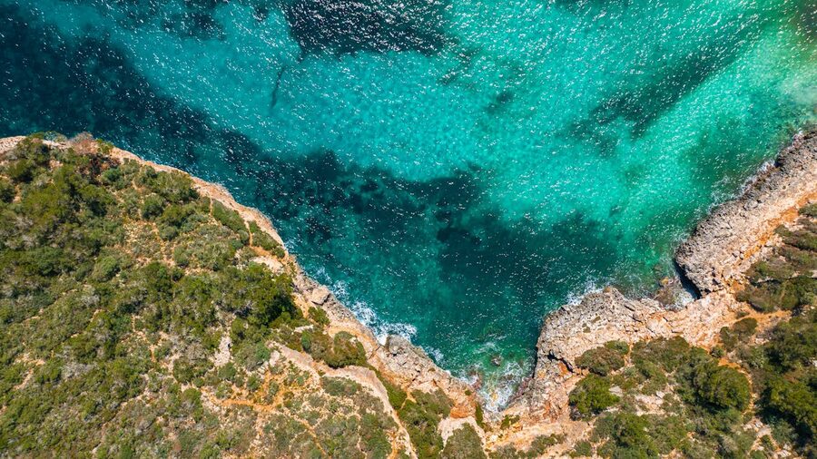 Stunning aerial view of rocky cliffs and clear turquoise sea along the Mallorca coastline