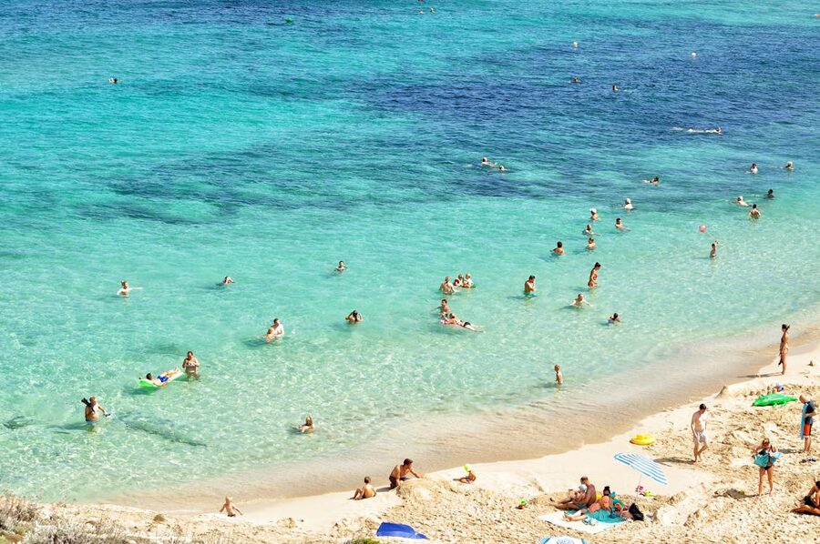 People enjoying a sunny day at a beautiful beach in Mallorca with turquoise waters