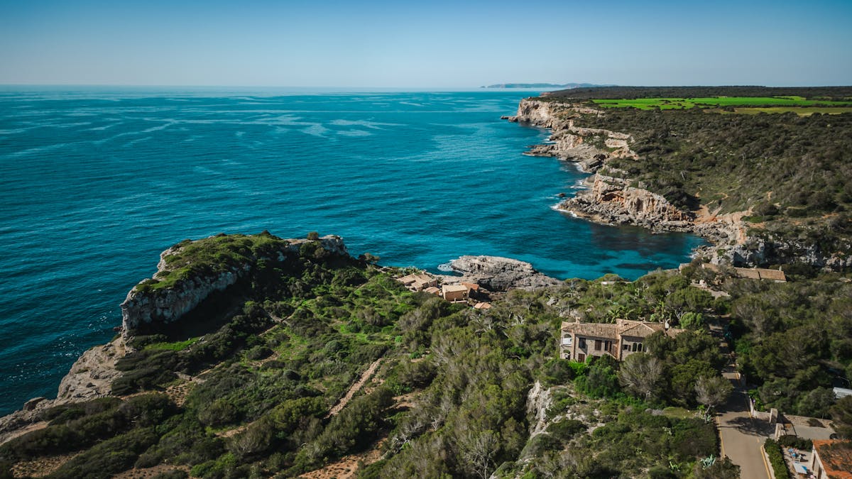 Aerial view of Mallorca rocky coastline with lush greenery and deep turquoise Mediterranean sea