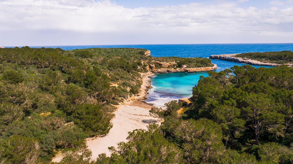 Aerial photograph of a small secluded beach between rocky cliffs in Mallorca