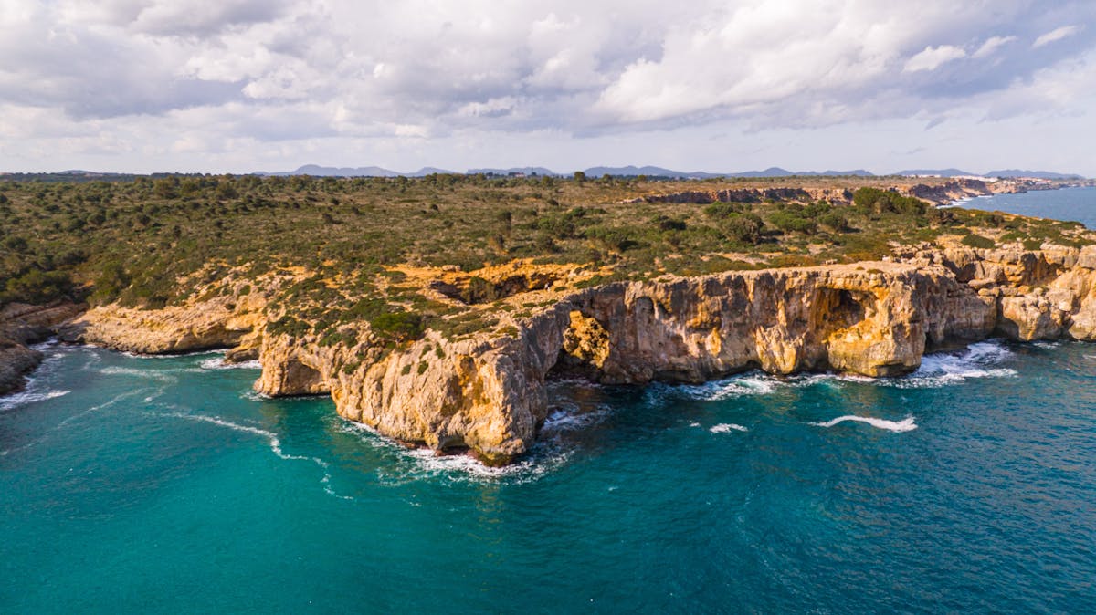 Towering rocky cliffs along the Mallorca coast with bright turquoise sea below