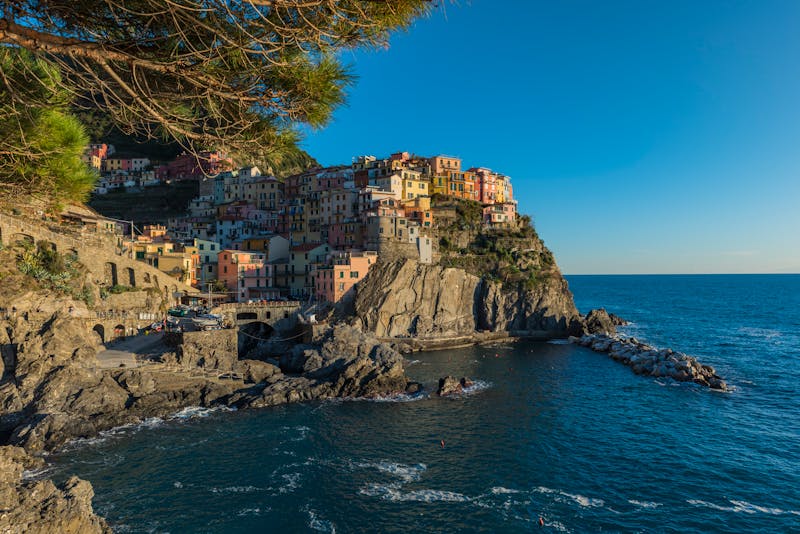 The colorful village of Manarola glowing in warm sunset light, perched on rugged cliffs above the Ligurian Sea