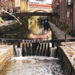 Historic canal bridges reflecting in still water in Castlefield Manchester