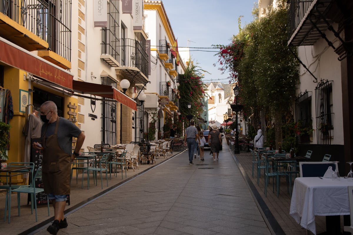 People walking through Marbella old town street with outdoor cafes
