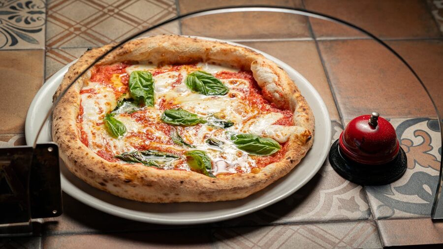 Close-up of a Margherita pizza with fresh basil on a rustic tiled table