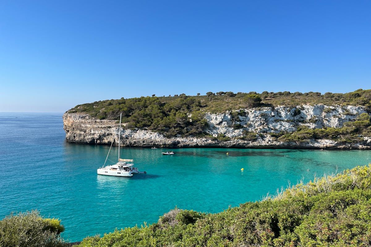 A single sailboat anchored in a calm turquoise bay along the Ibiza coast