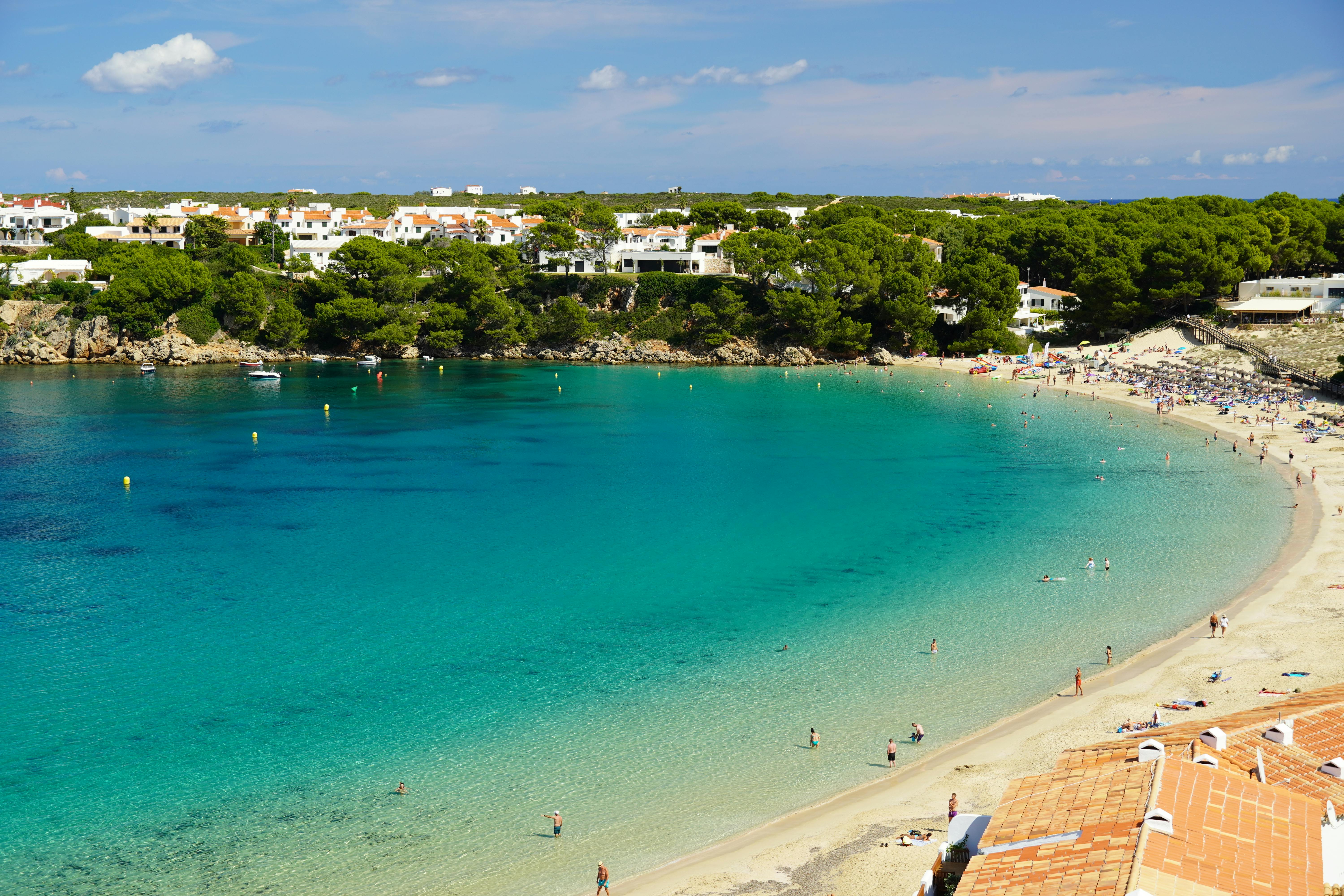 Beach in Menorca with clear waters surrounded by limestone cliffs
