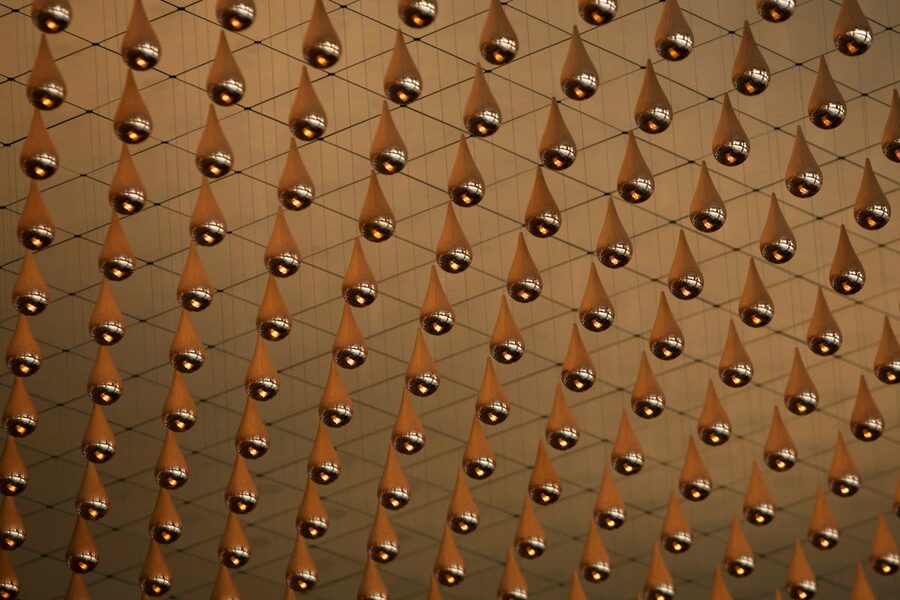 Metallic droplets suspended in an intricate net pattern creating an immersive art installation