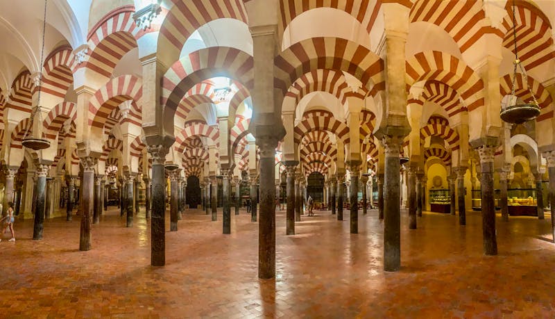 The iconic red and white striped arches inside the Mosque-Cathedral of Cordoba stretching into the distance