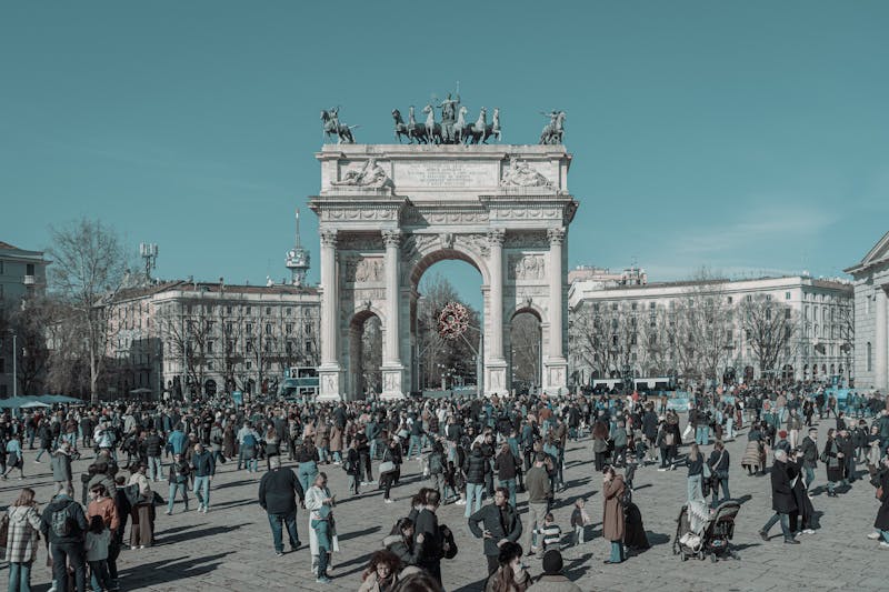 Arco della Pace in Milan with diverse people walking under a clear sky