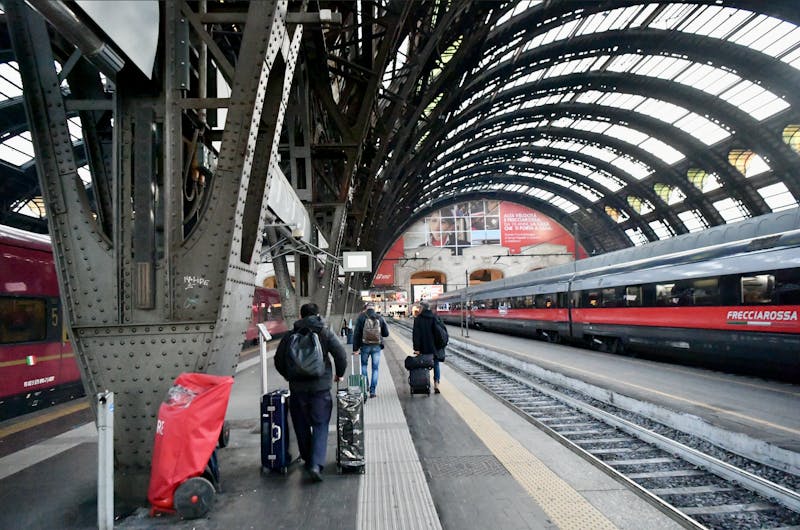 Travelers walking through Milan Central Station under arched ceilings