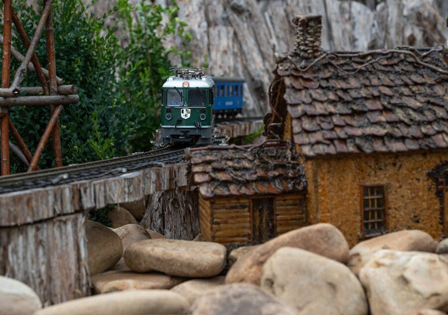 Model train crossing a wooden bridge amidst miniature houses