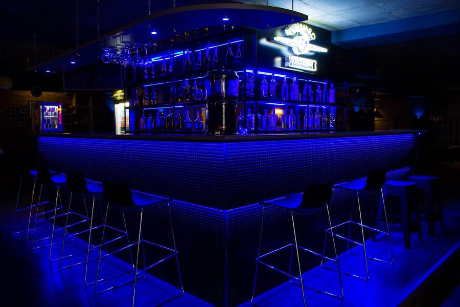 A sleek modern bar counter with blue neon lighting