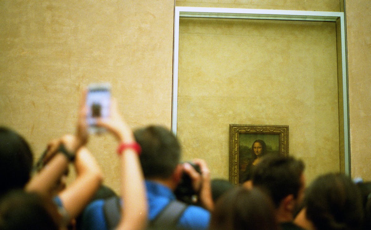 Visitors in the Louvre Museum capturing the Mona Lisa painting with smartphones