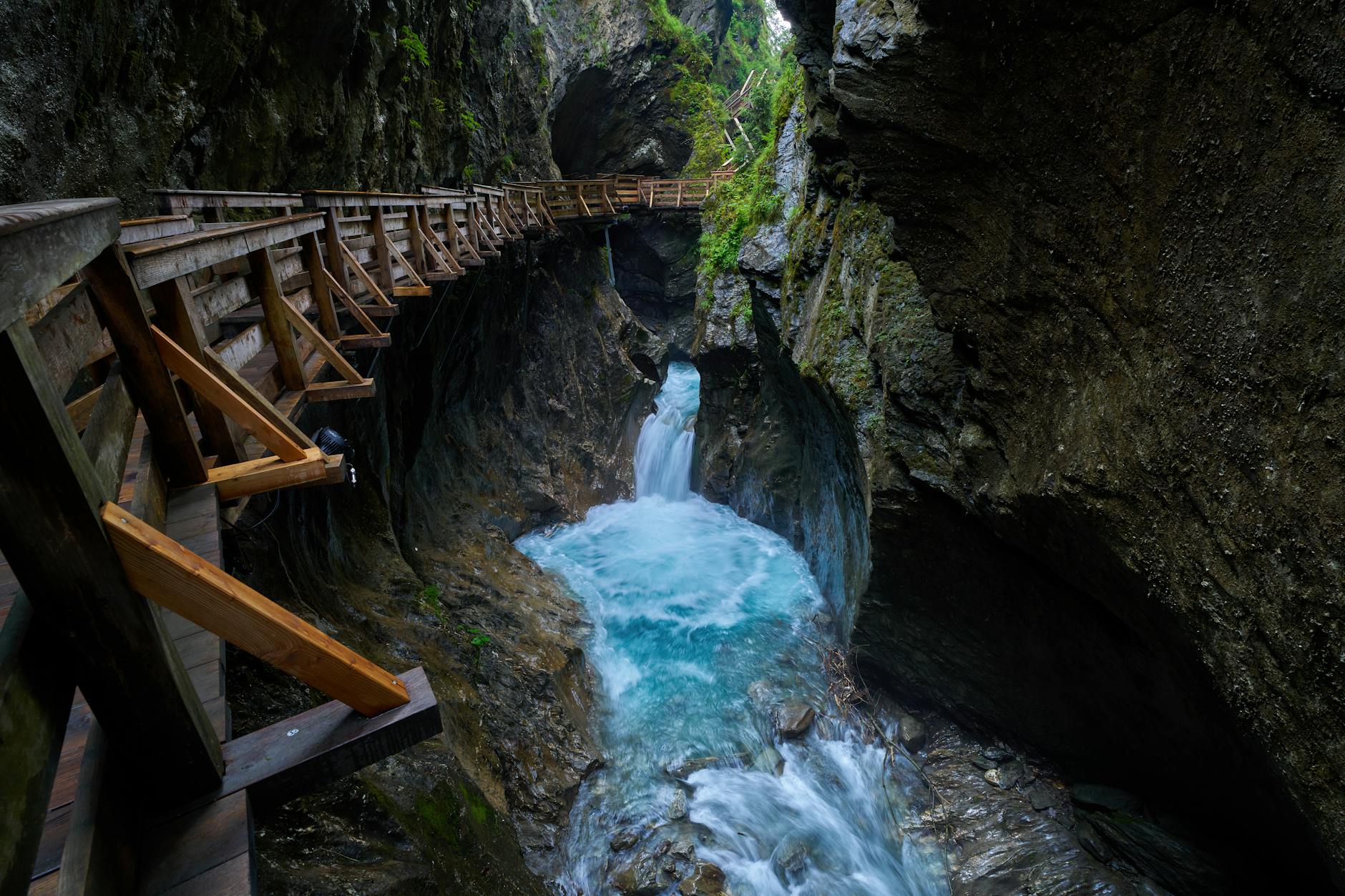 Waterfall cascading into gorge with wooden walkway