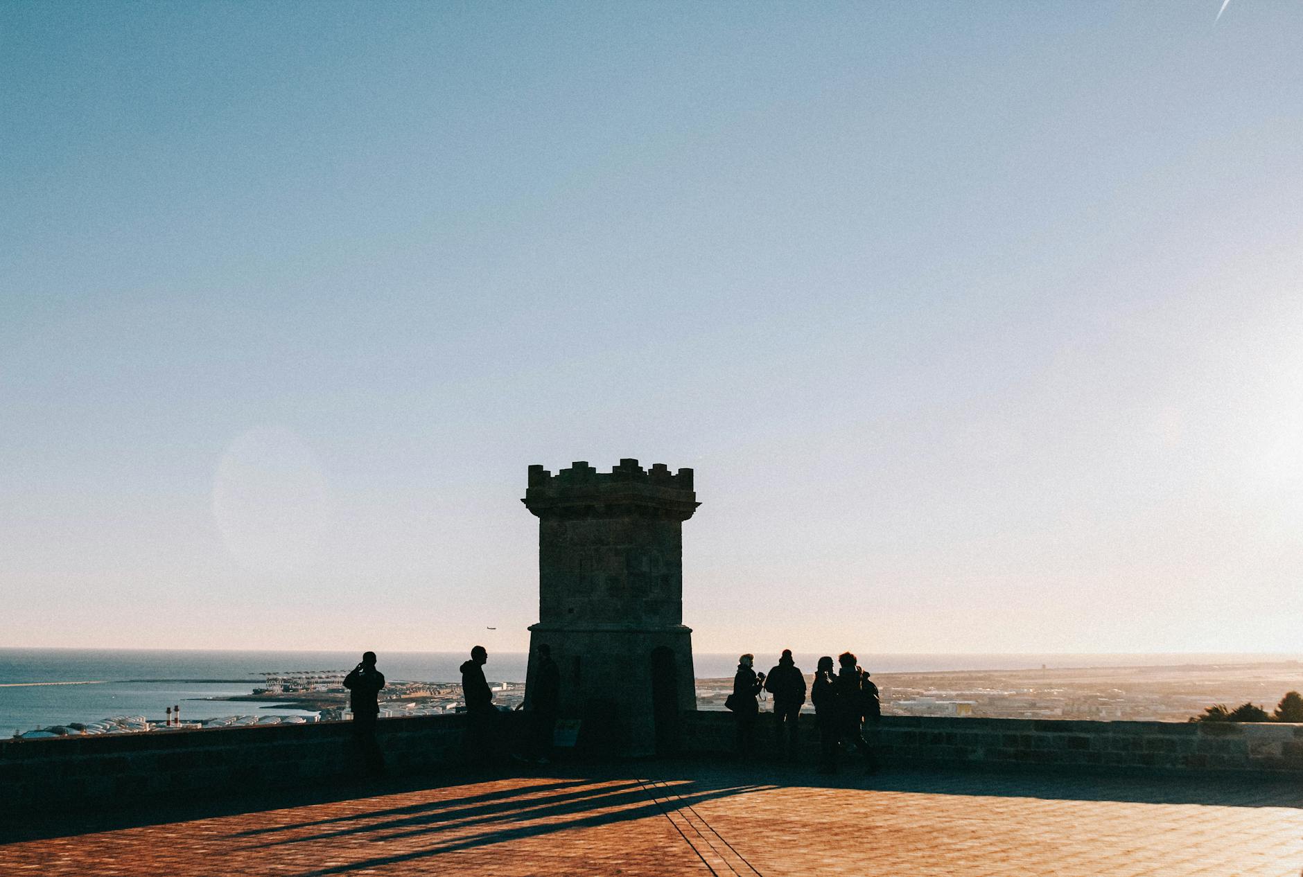 Silhouetted figures at Montjuic Castle in Barcelona enjoying sea views during sunset