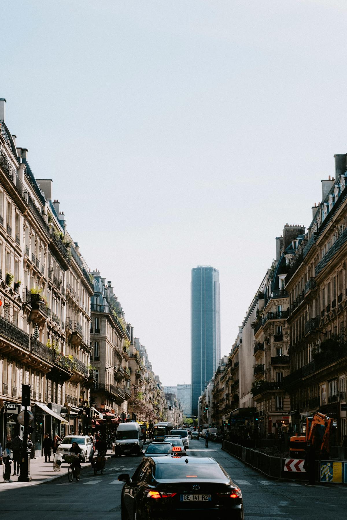 Busy Paris street featuring Montparnasse Tower with cars and pedestrians