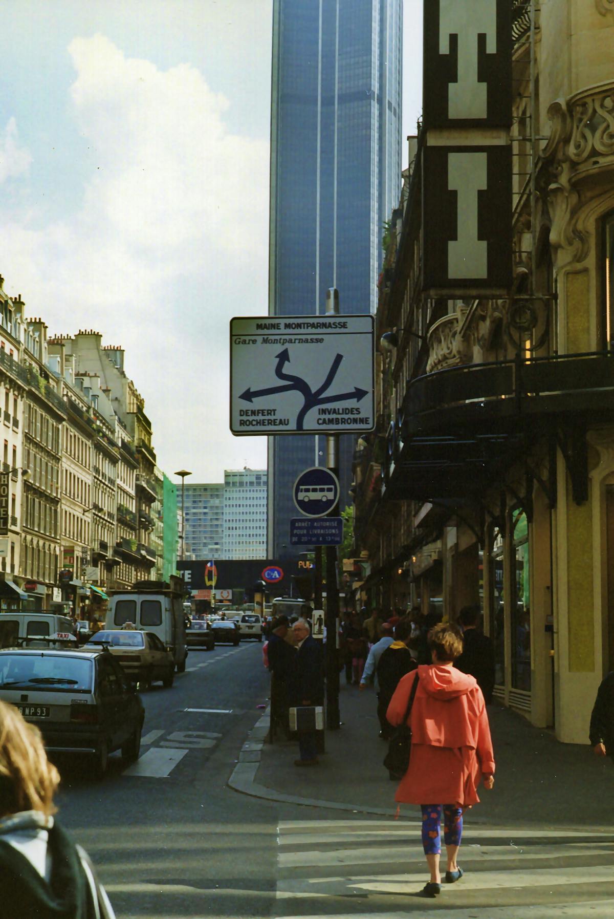 Paris street scene with pedestrians and Montparnasse Tower visible behind buildings