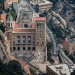 Aerial view of Montserrat Abbey surrounded by jagged rock formations and tourists