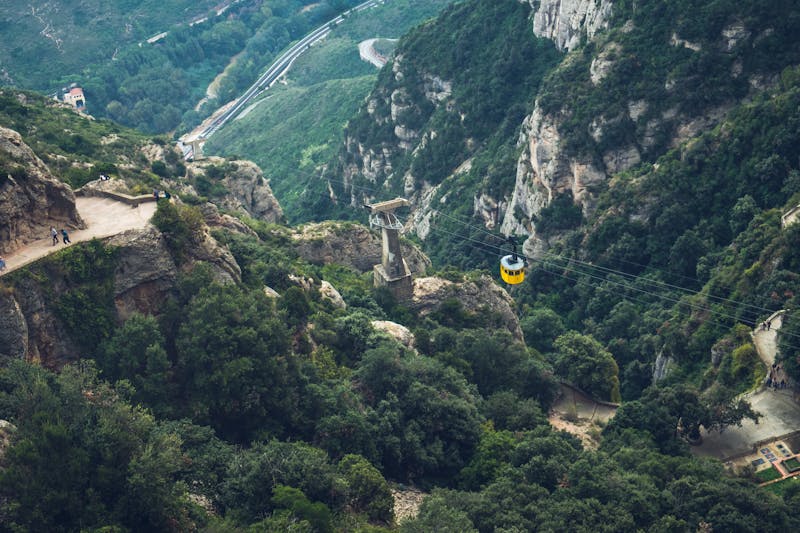Yellow cable car suspended above lush green mountains at Montserrat