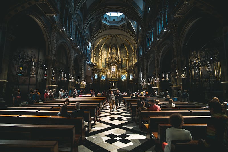 Spacious interior of Montserrat Abbey with tall columns and visitors walking through