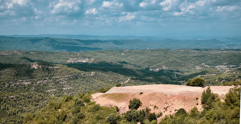 Lush green plateau on Montserrat mountain with dramatic rock peaks in the distance