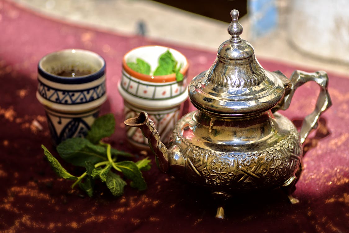 Traditional Moroccan silver teapot and ornate cups with fresh mint tea